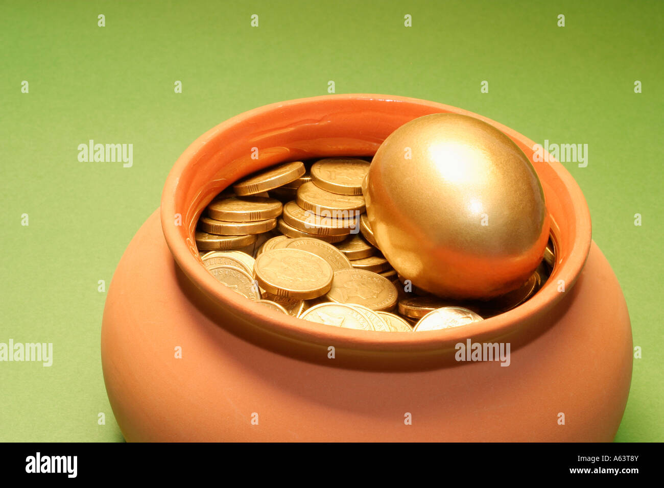 Clay Pot with Coins and Golden Egg Stock Photo - Alamy
