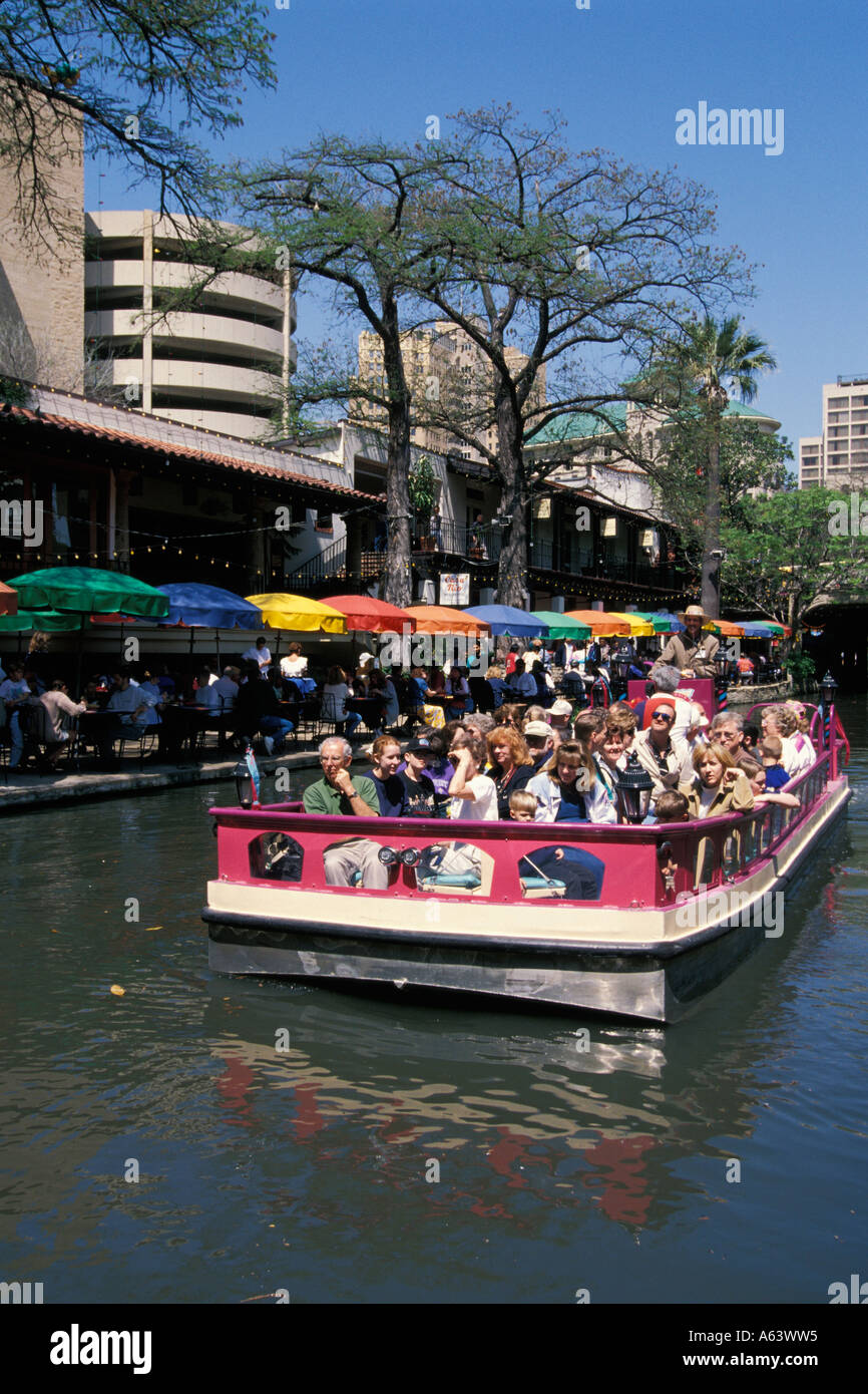 Water taxi or tour boat on San Antonio River passes people dining under ...