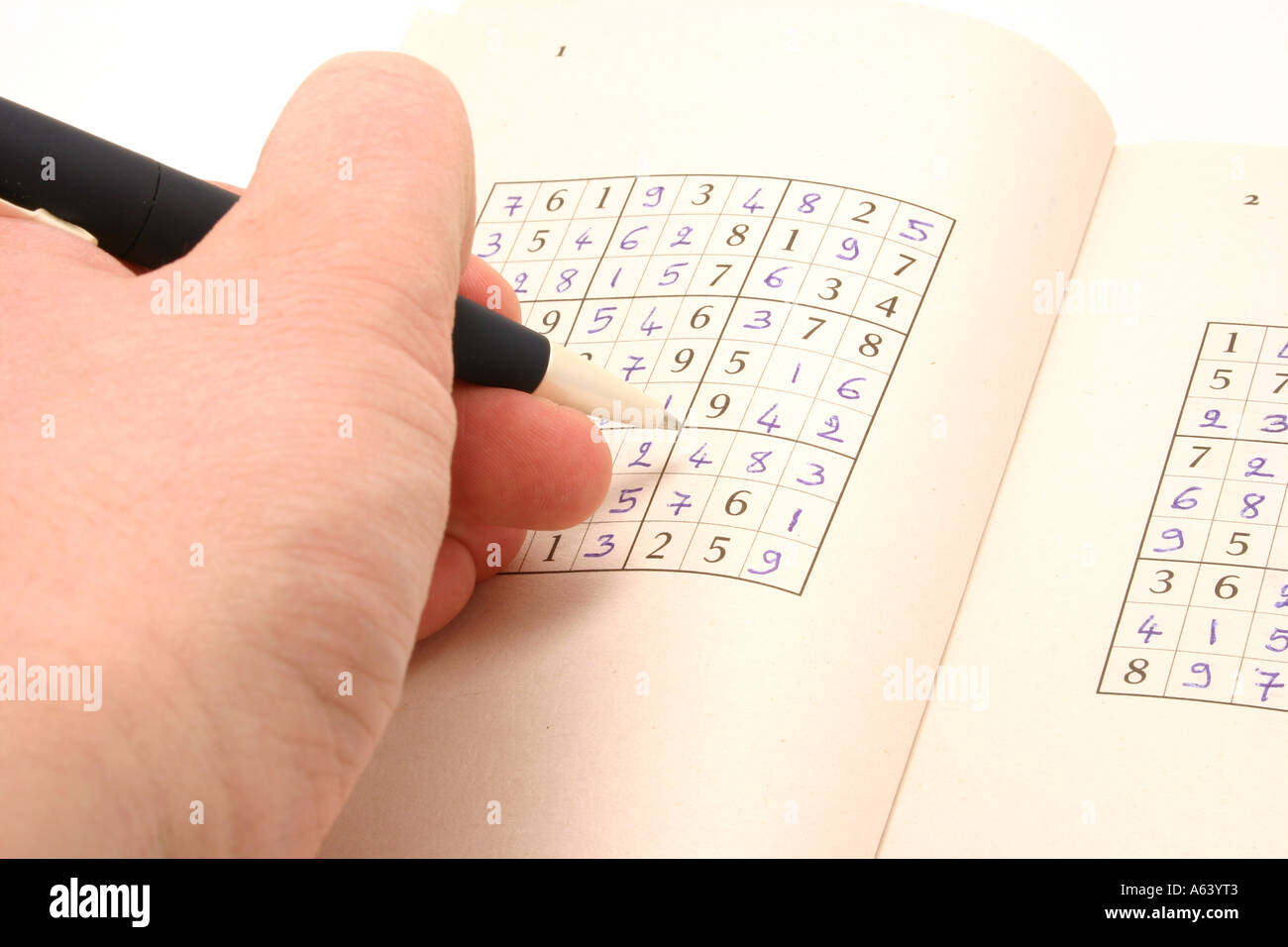 Su doku or Sudoku game on a book with a hand and a pen Stock Photo - Alamy