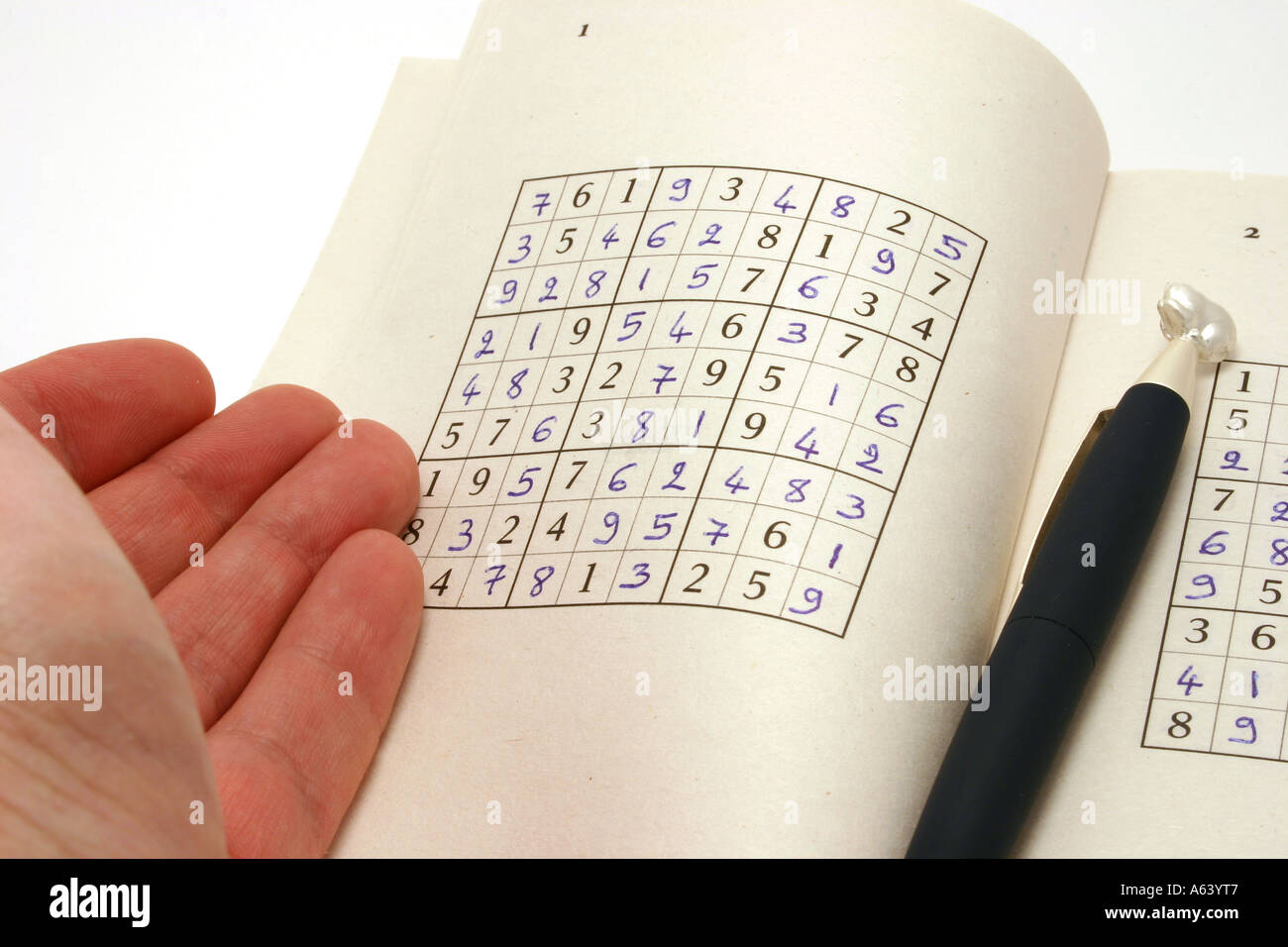 Su doku or Sudoku game on a book with a hand and a pen Stock Photo - Alamy