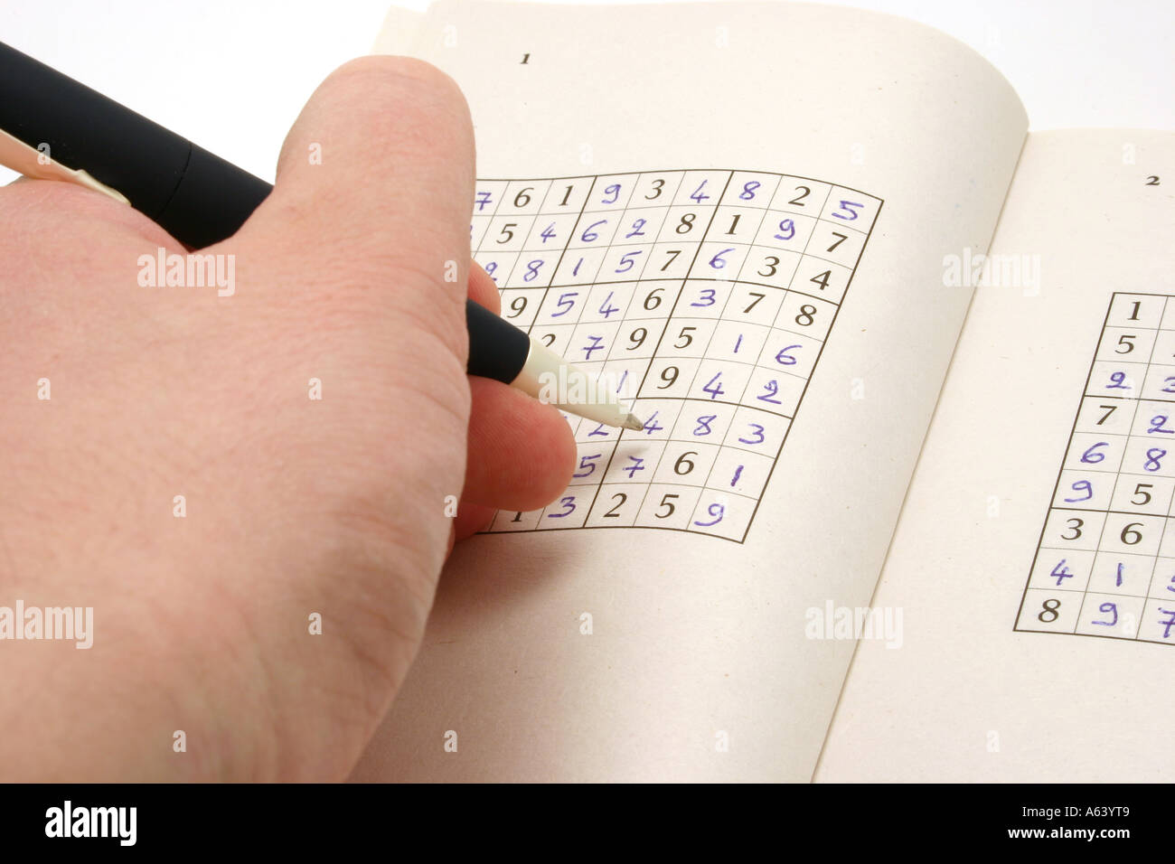 Su doku or Sudoku game on a book with a hand and a pen Stock Photo - Alamy