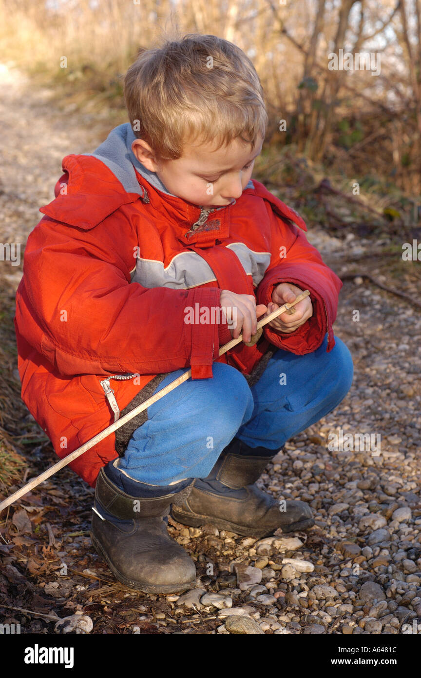 Five year old boy tinkering with a stick Stock Photo - Alamy