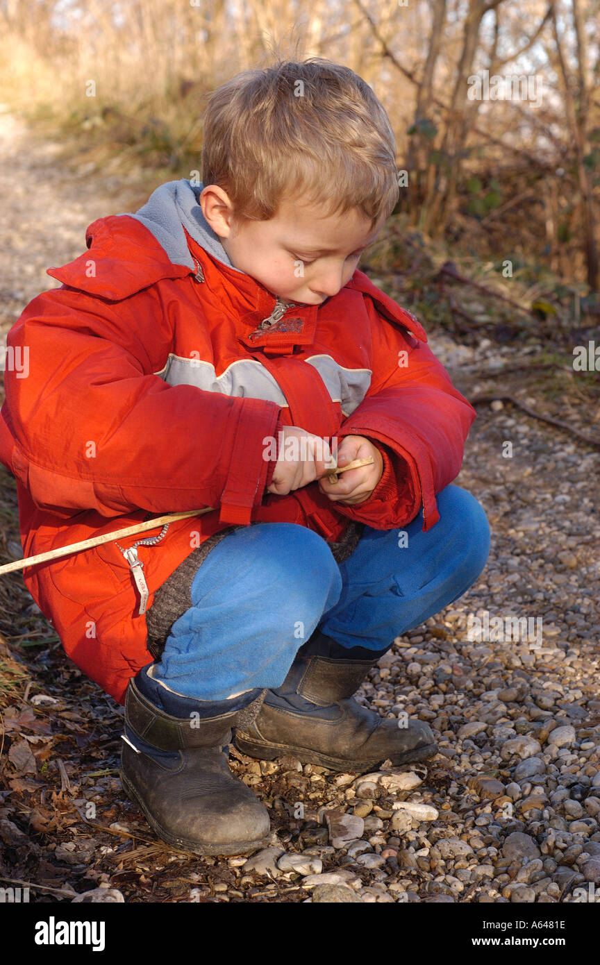 Five year old boy tinkering with a stick Stock Photo - Alamy