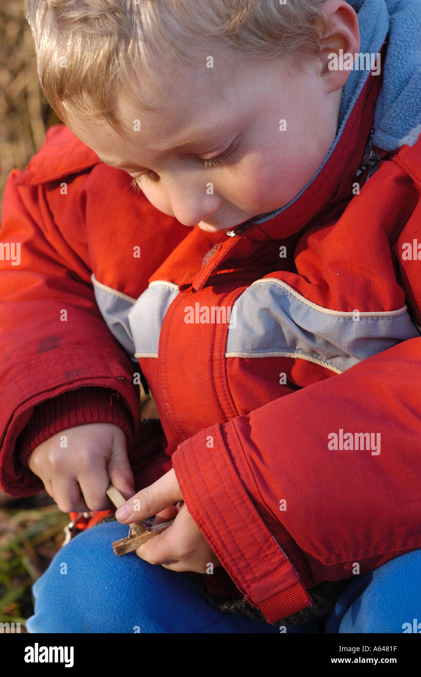 Five year old boy tinkering with a stick Stock Photo - Alamy