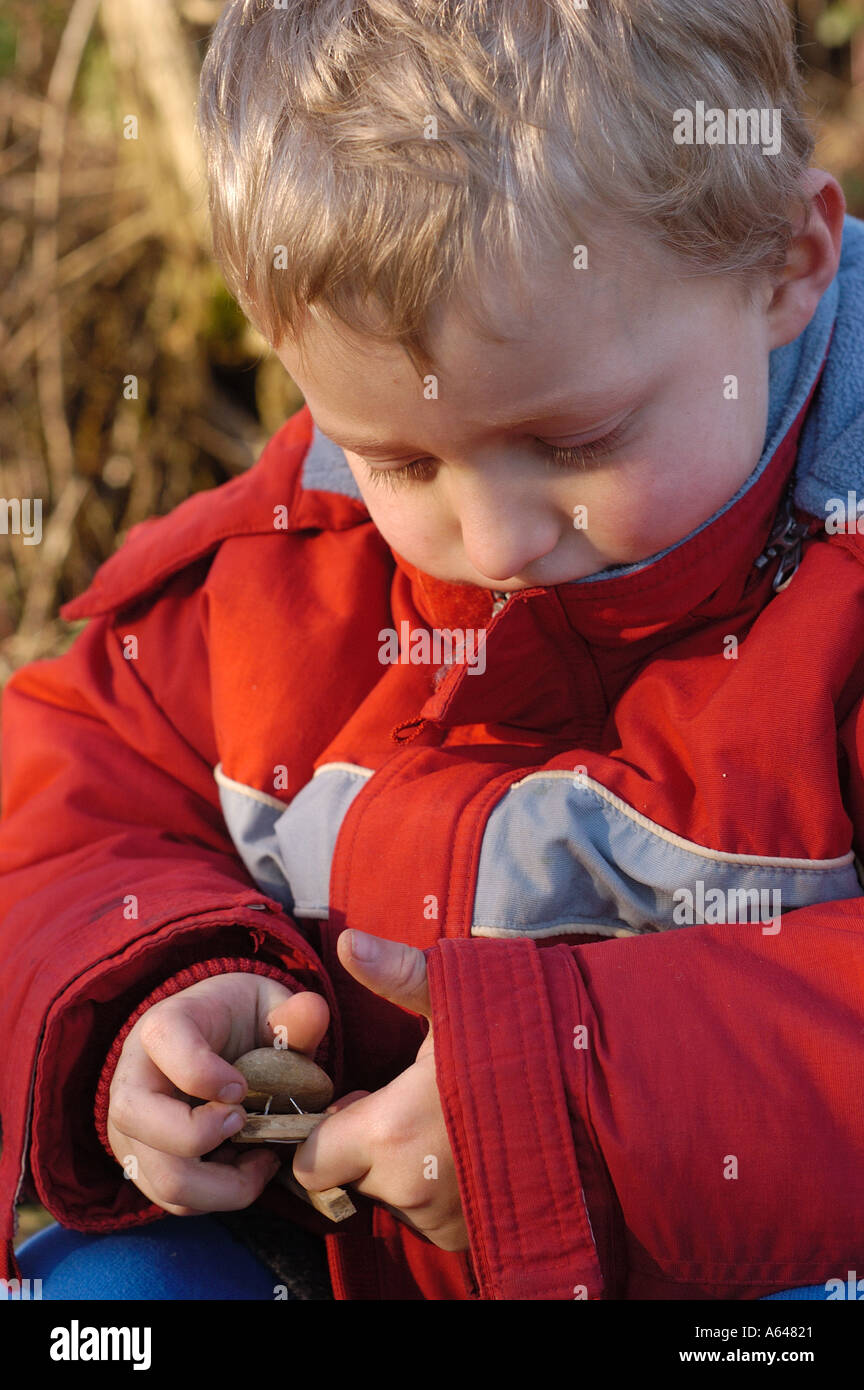 Five year old boy tinkering with a stick Stock Photo - Alamy