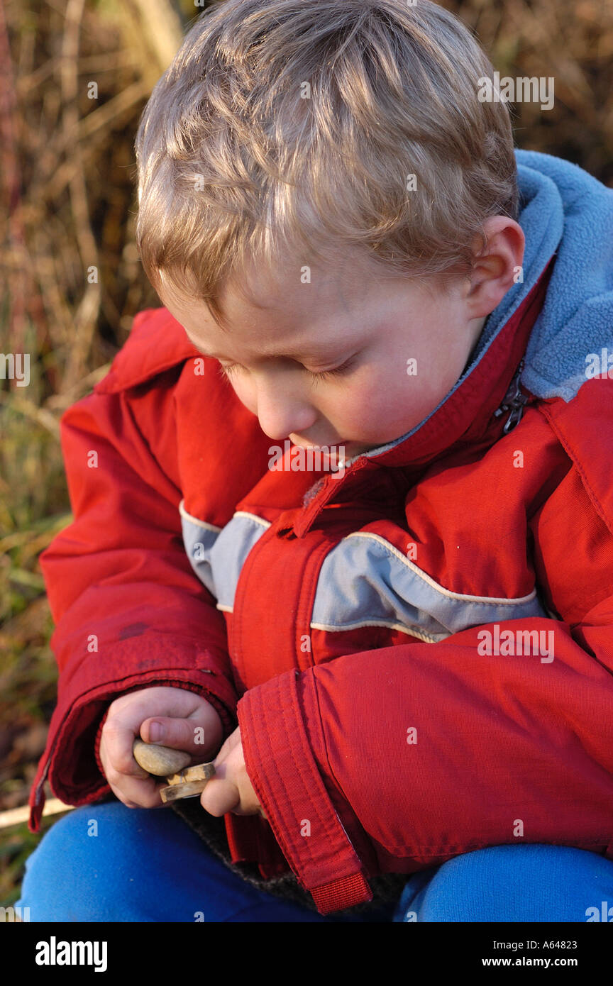 Five year old boy tinkering with a stick Stock Photo - Alamy