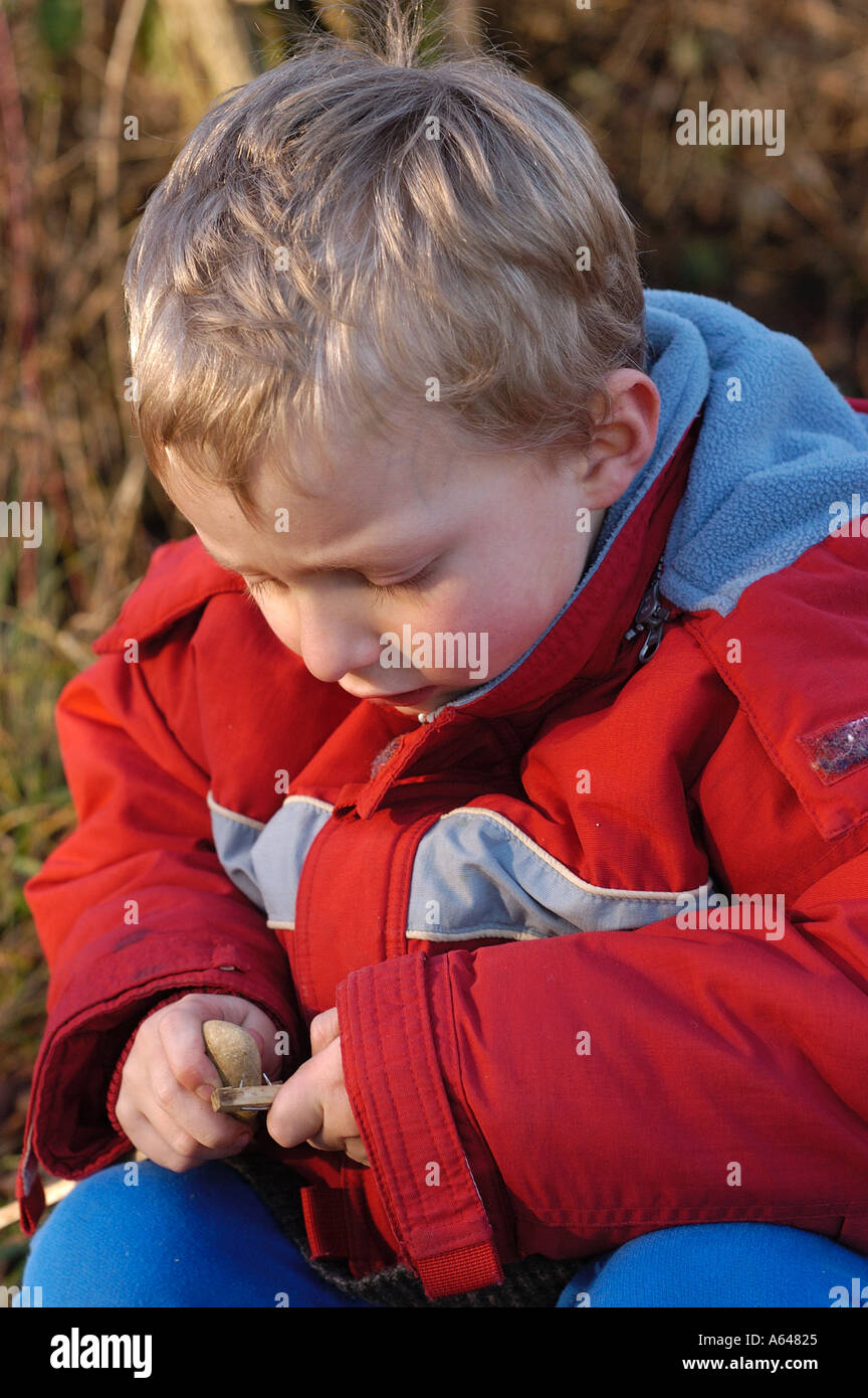 Five year old boy tinkering with a stick Stock Photo - Alamy