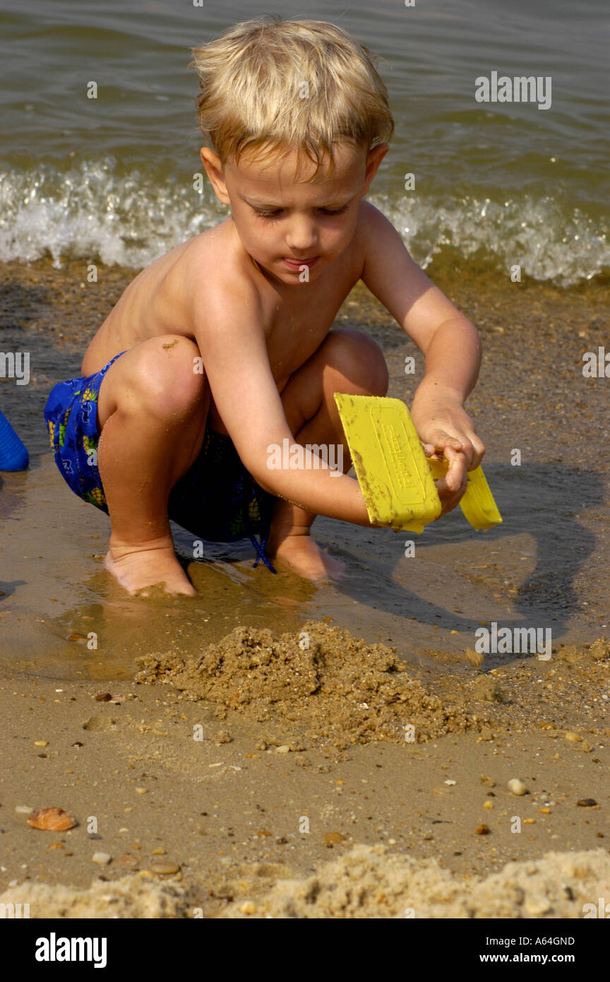 Young boy playing on beach digging in sand family summer vacation Stock ...