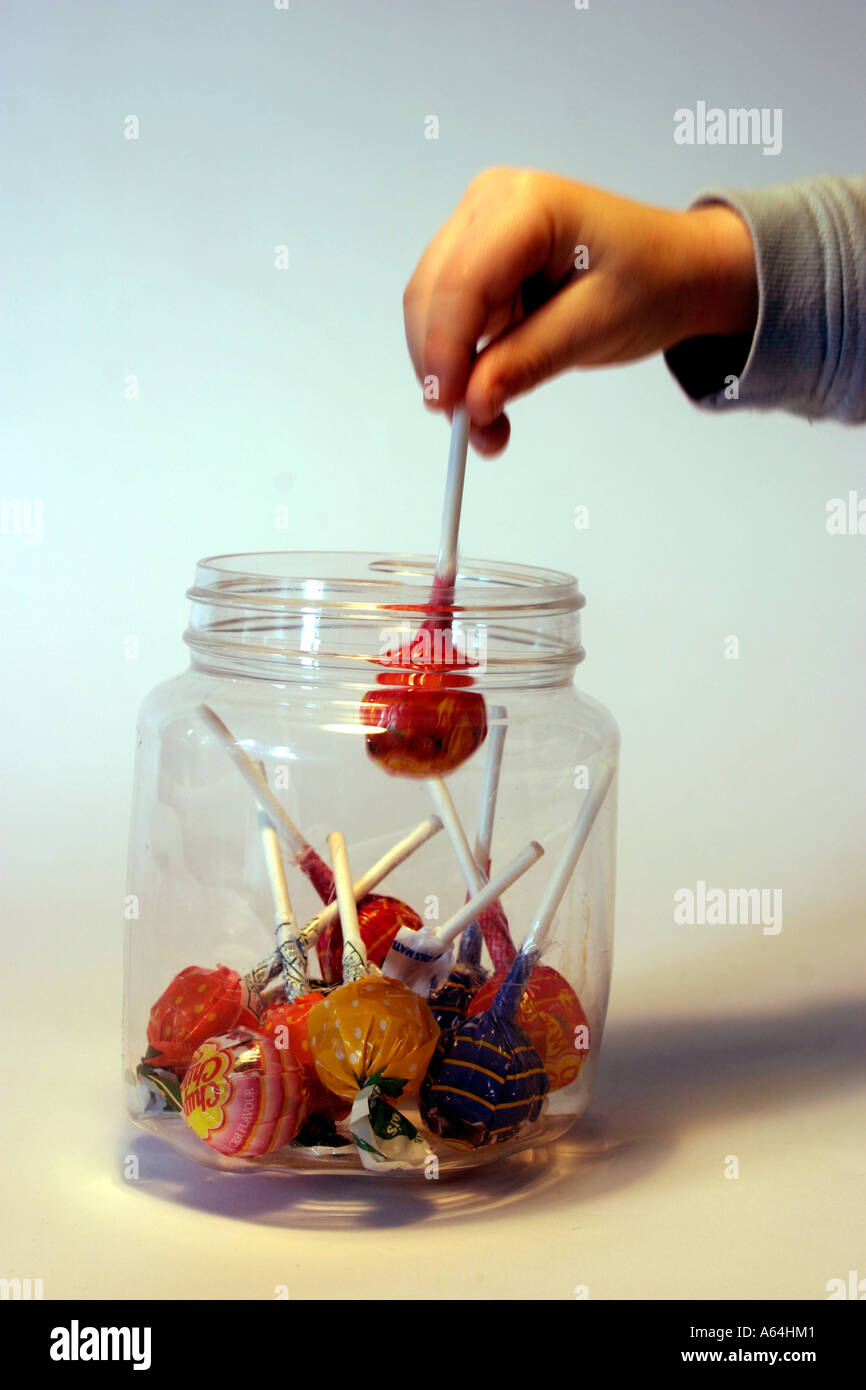 A hand taking a lollipop sweet from a selection of Lollipop sweets in a ...
