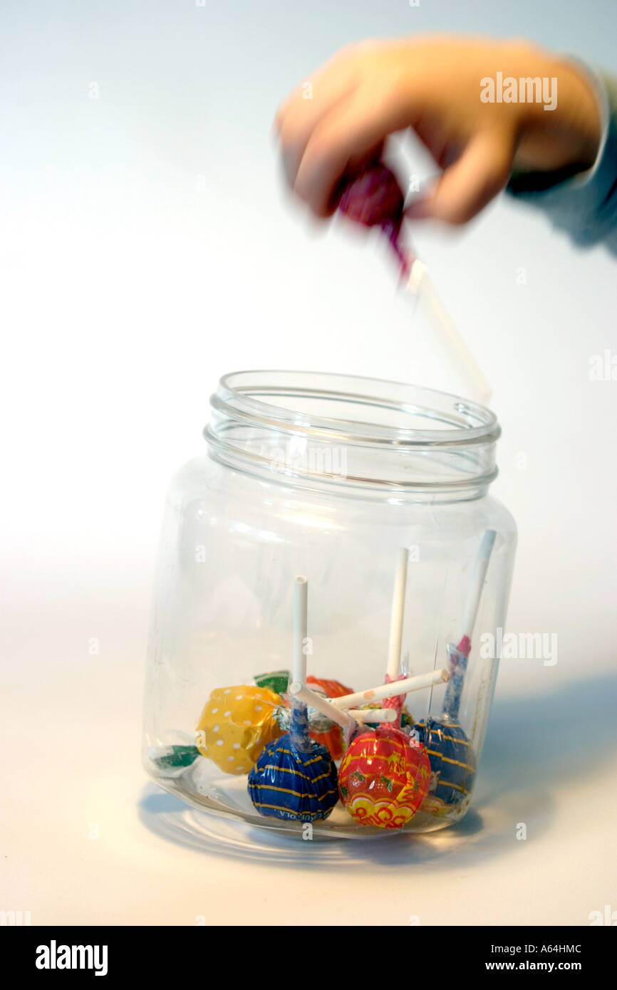A hand taking a lollipop sweet from a selection of Lollipop sweets in a ...