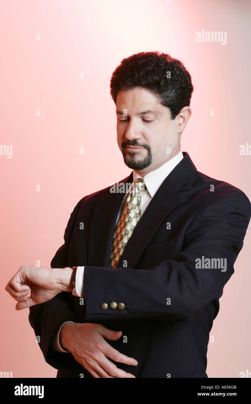 Man dressed in suit with a looks at his watch Stock Photo - Alamy