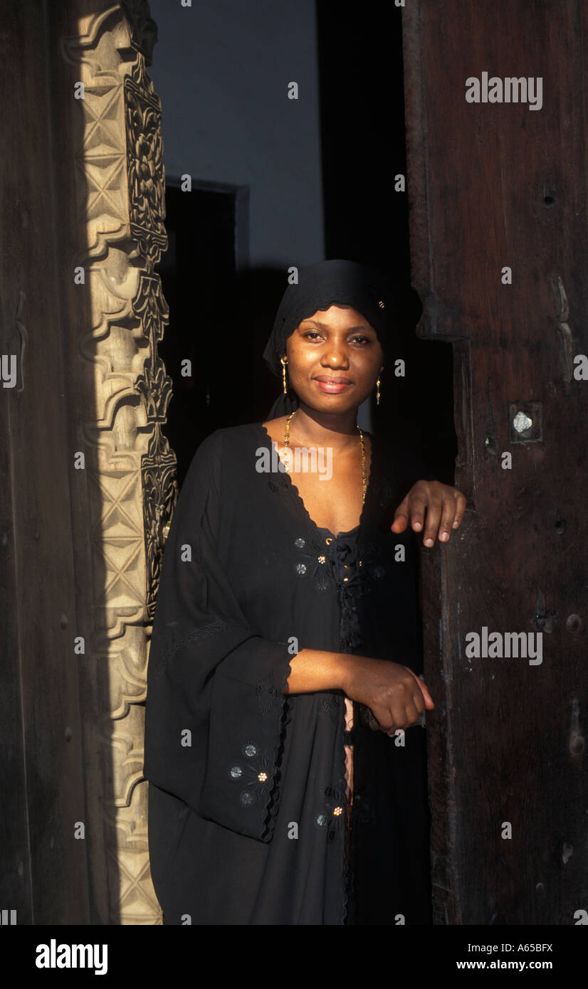Swahili woman wearing a traditional bui bui standing in a Zanzibar doorway Zanzibar Tanzania ...
