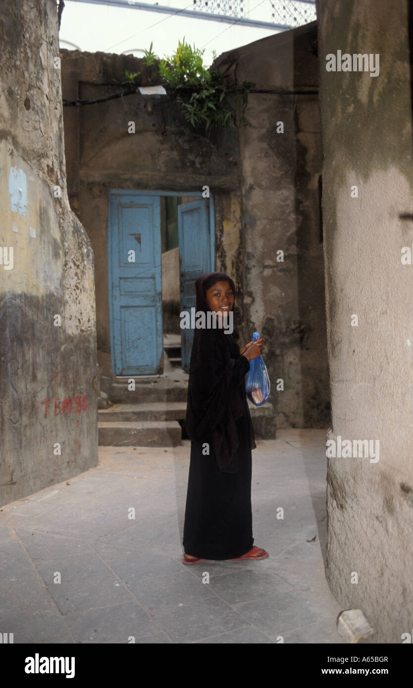 girl wearing a black bui bui walking in a narrow alley Stone Town ...