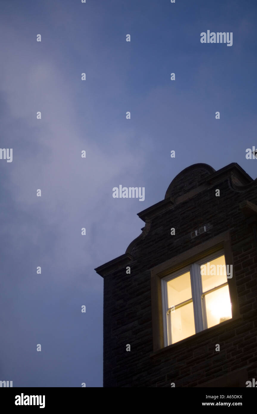 single illuminated Lighted window on top floor of building at night ...