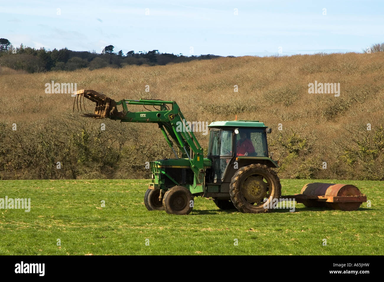 a tractor rolling a grazing field Stock Photo - Alamy