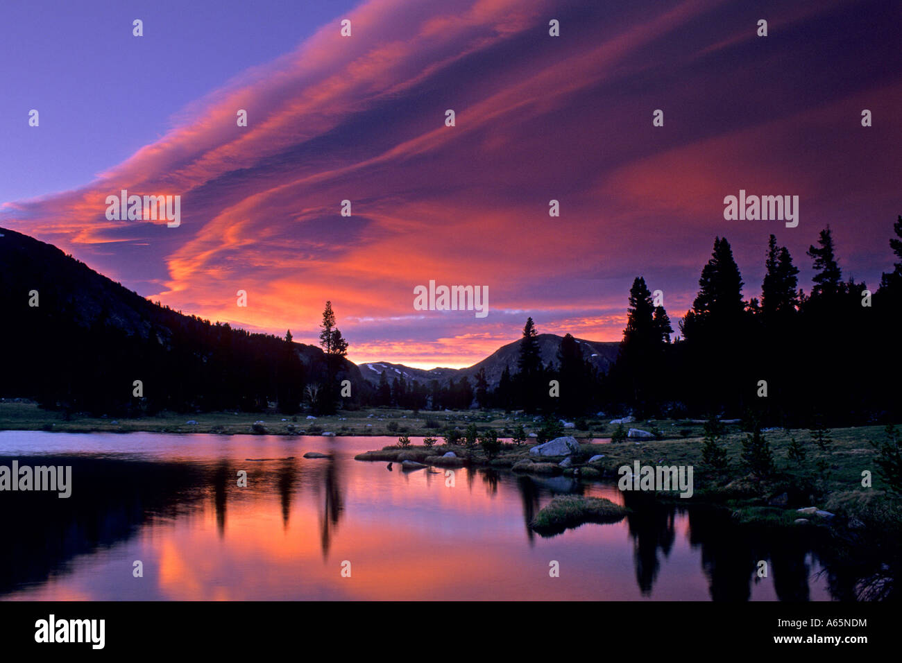 Lenticular wave cloud at sunset over an alpine tarn at Tioga Pass ...