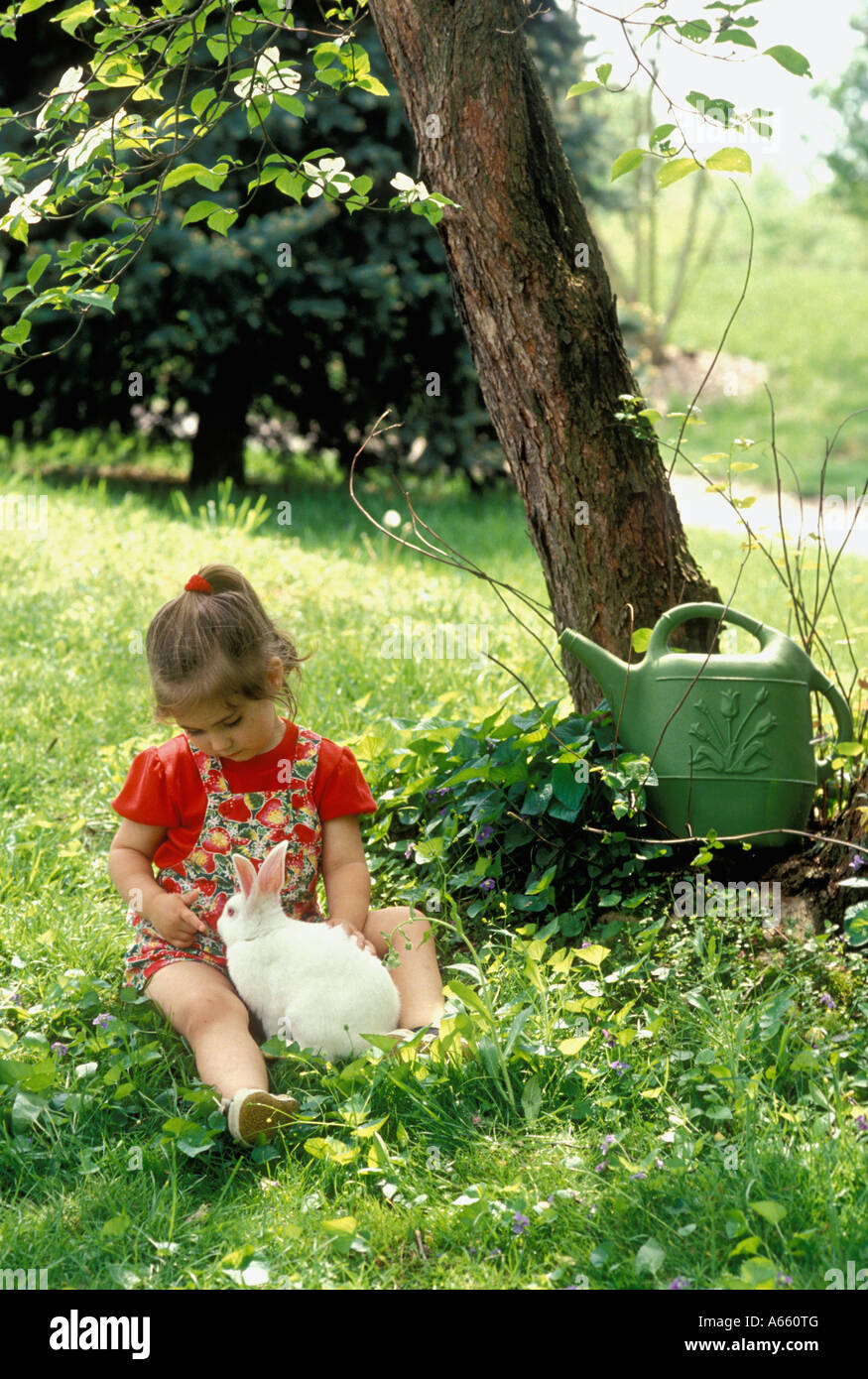 Young Girl Holding Bunny Rabbit in her Lap While Sitting in Spring ...