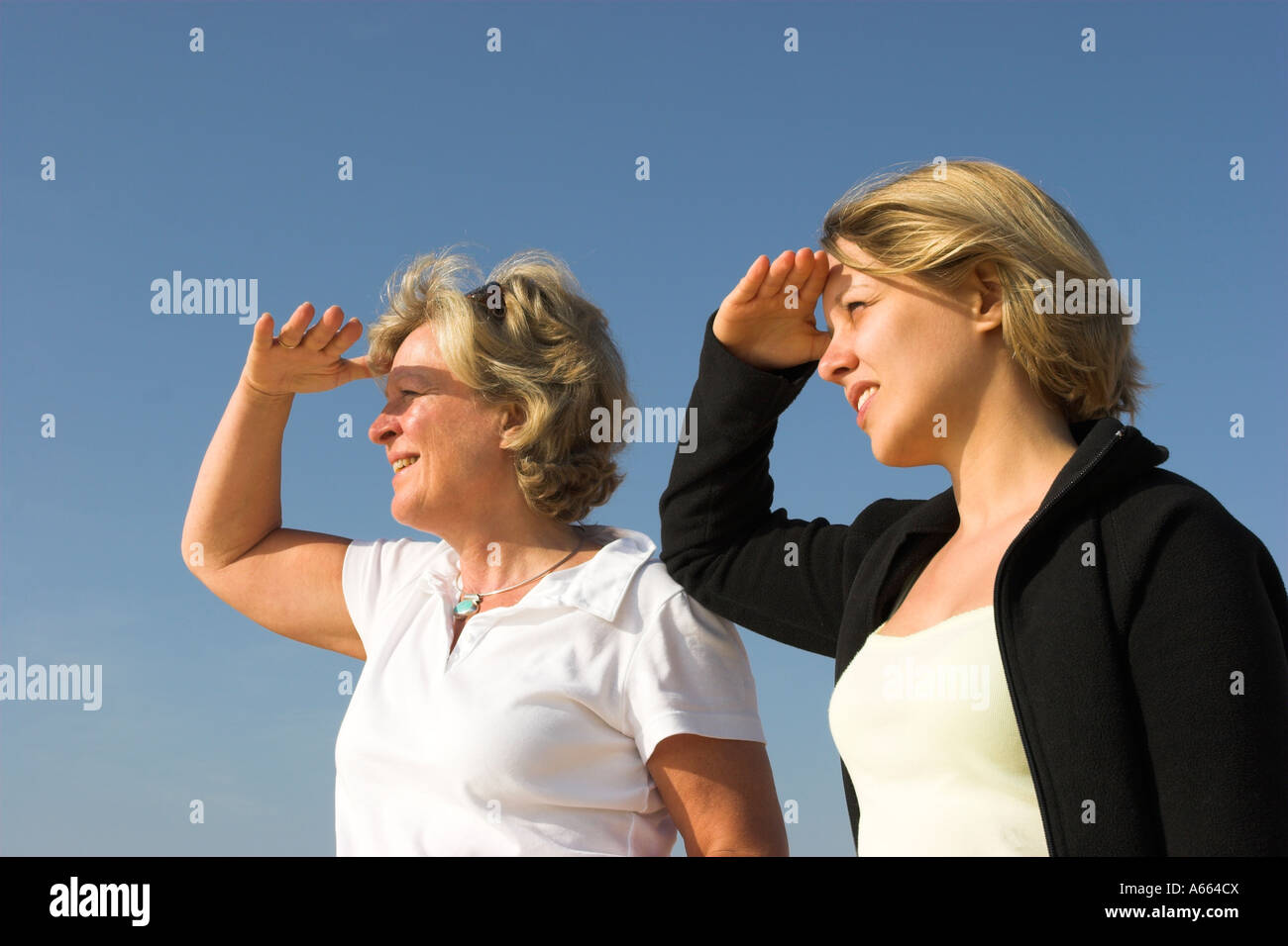 Two women shade their eyes as they look into the direction of the sun ...
