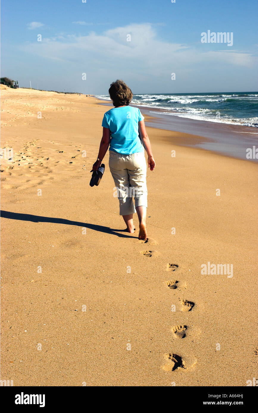 Single woman walking along the beach Stock Photo - Alamy