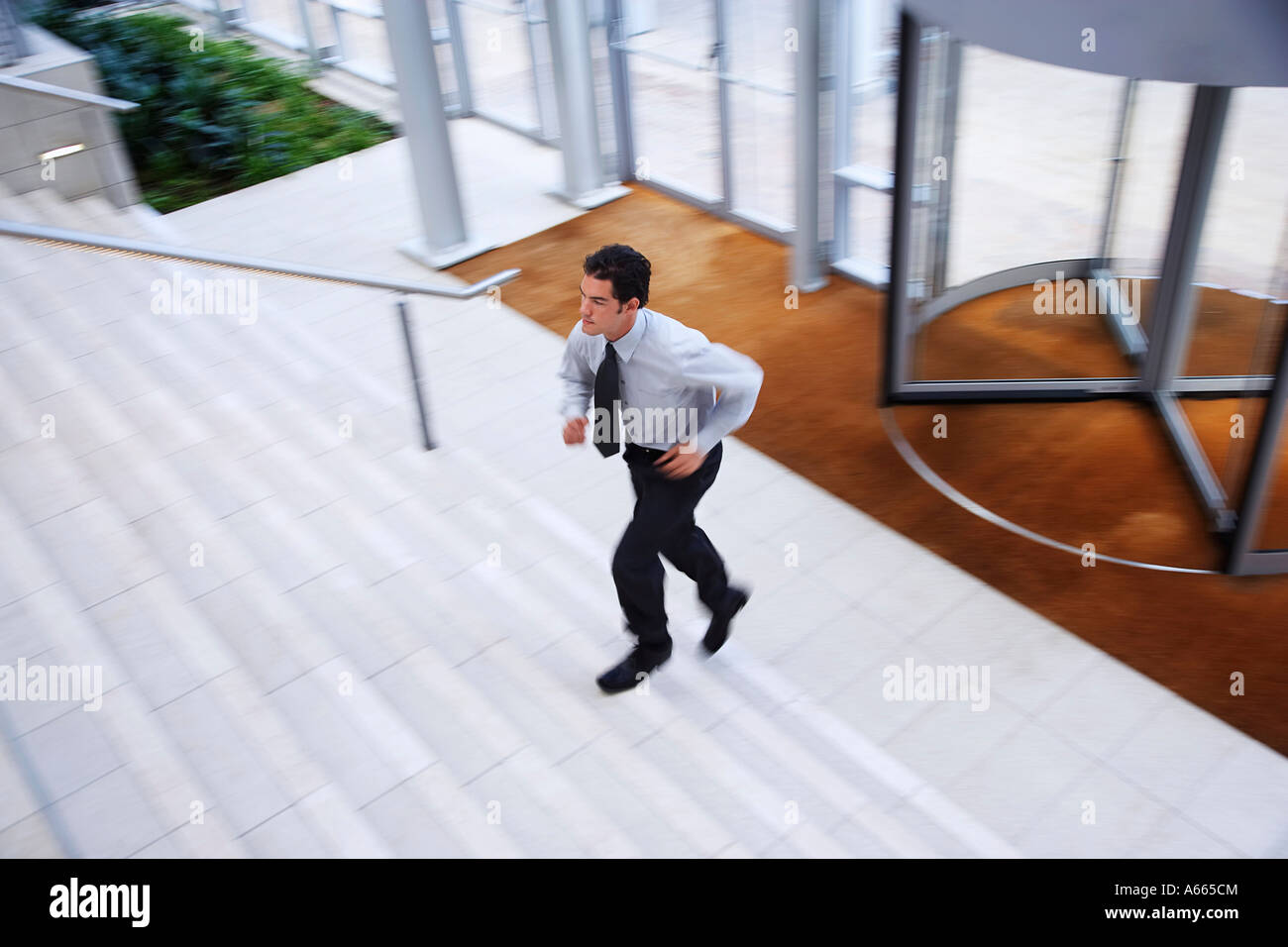 Businessman running up stairs in office lobby Stock Photo - Alamy
