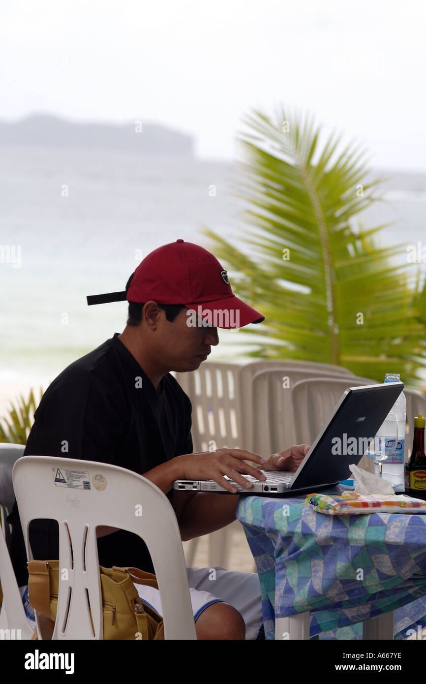 Filipino man from Manilla at his laptop computer on a working vacation ...
