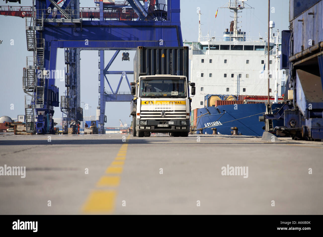 a lorry loading onto a container ship in a busy port Stock Photo - Alamy