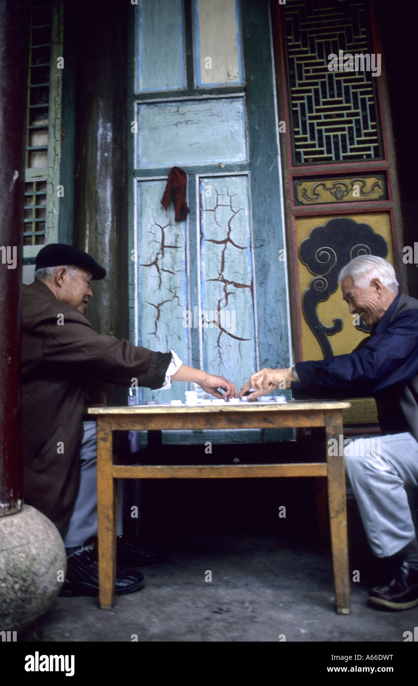 Two elderly men playing game of draughts in front of a temple entrance ...