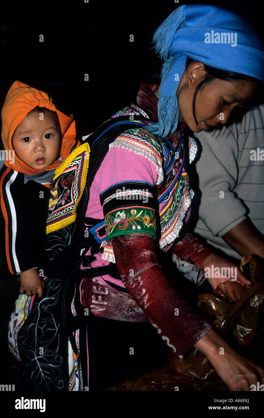 Night scene : Woman of Yi ethnic minority in traditional dress, carrying her child on the back ...