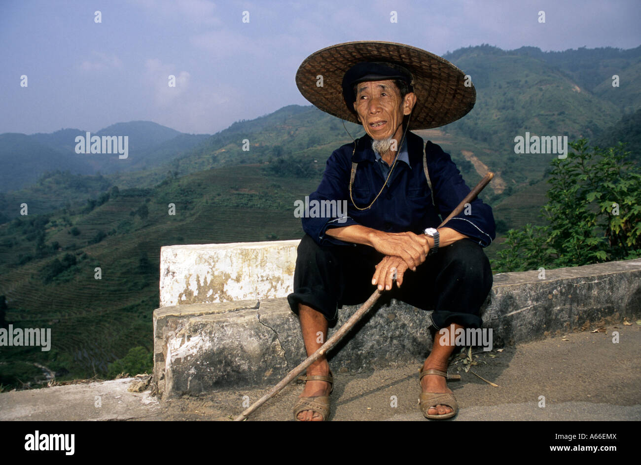 Old man with grey goatee and broad rim straw hat sitting by the side of ...