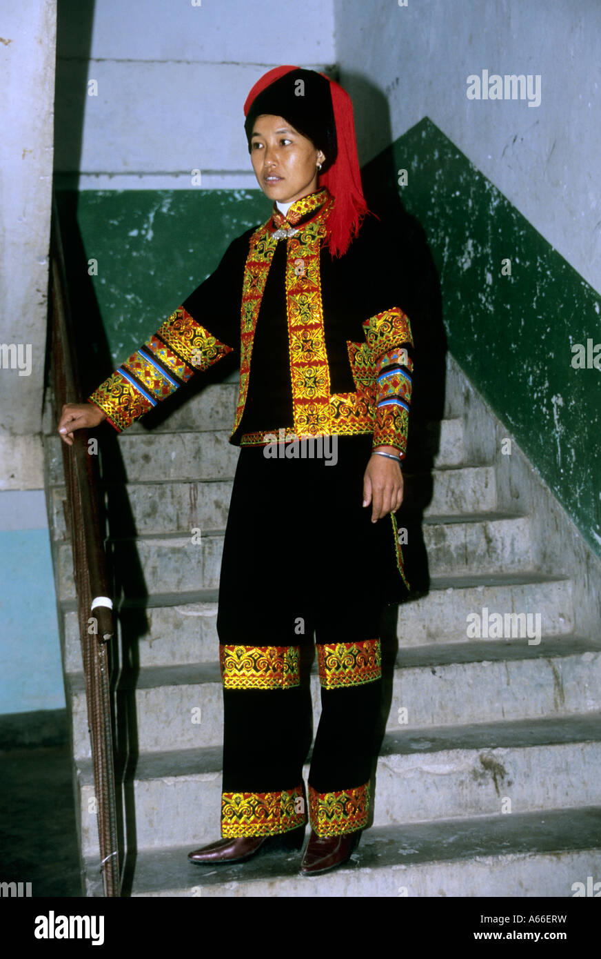 Woman of Hani ethnic minority in traditional dress on stairs of her ...