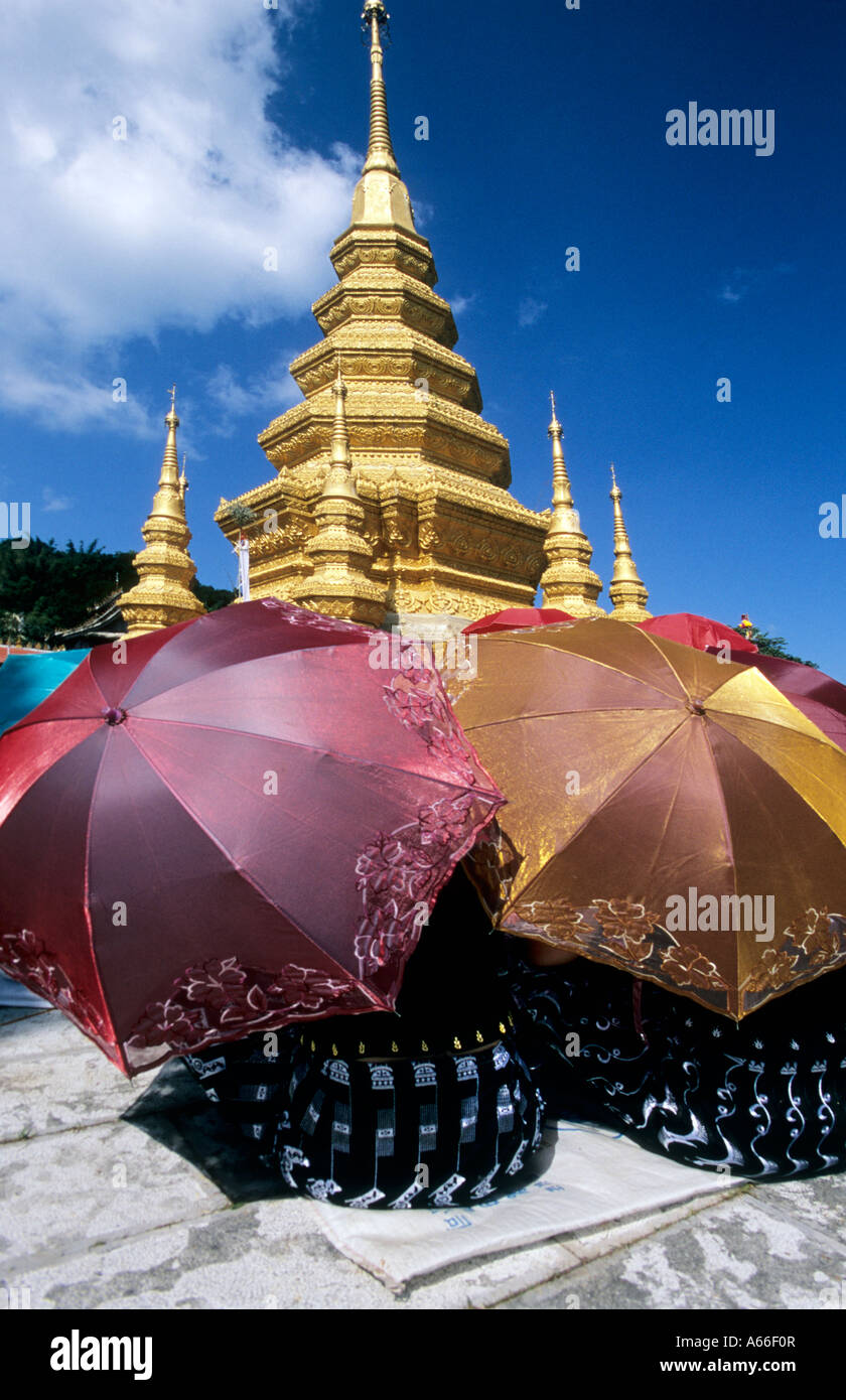 Women with colourful silk umbrellas in front of a golden pagoda in ...