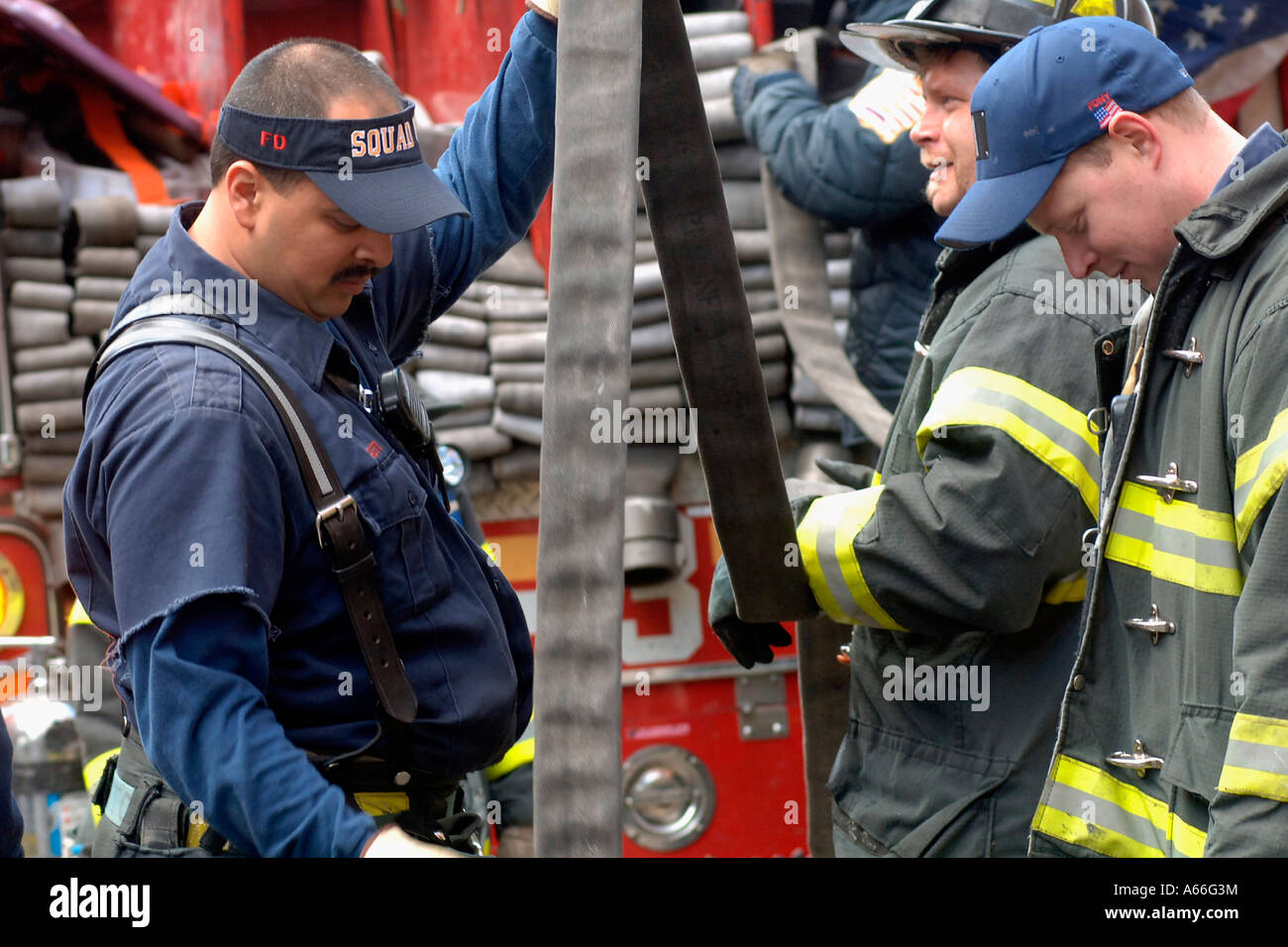 FDNY firefighters collect their hoses after fighting a fire in the ...
