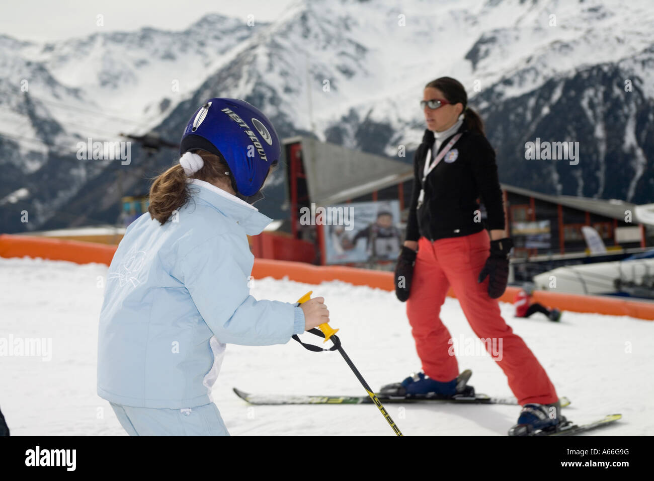 Young girl with ski teacher for a lesson on the snow Stock Photo - Alamy
