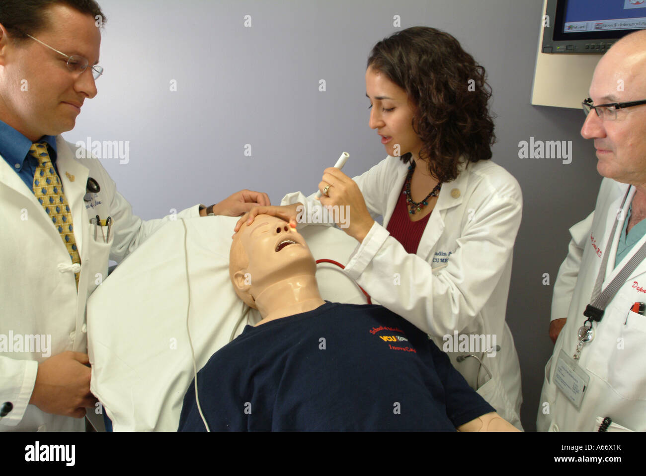A female med student shines a small flashlight in the eye of a SimMan A ...