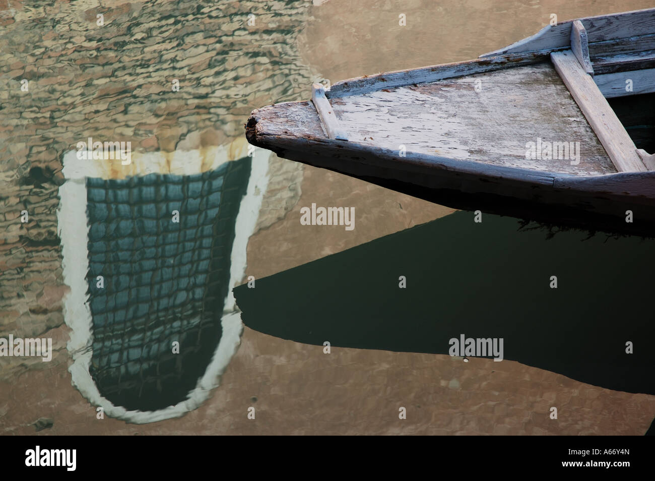 Bow of an old wooden Venetian rowboat with the reflection of a window ...