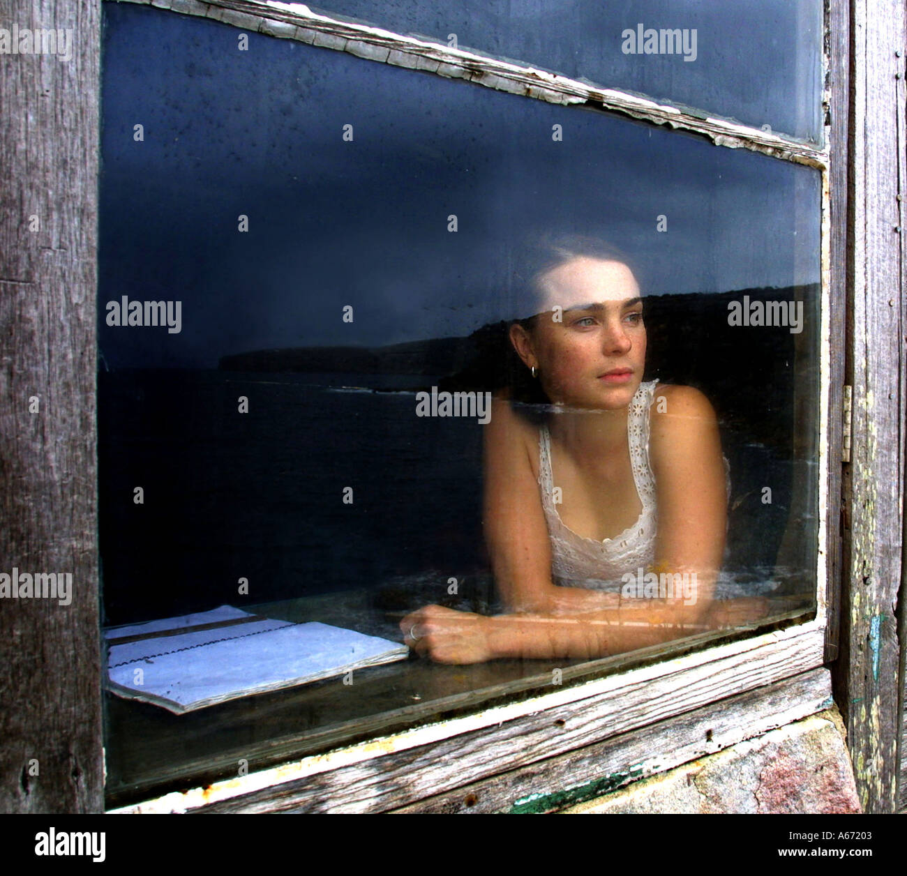 A young woman looks out a window of an isolated hut Stock Photo - Alamy