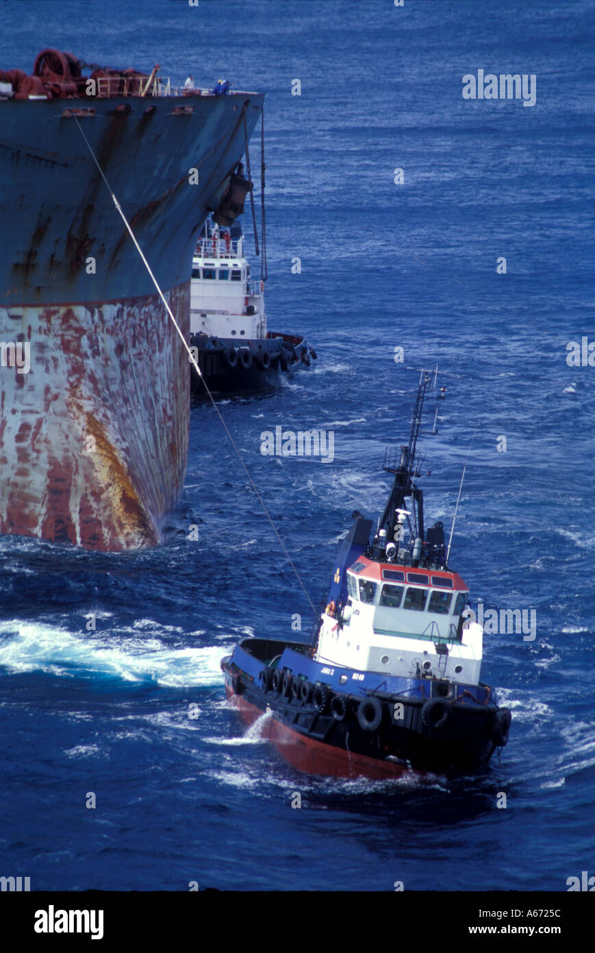 Tug boat towing big tanker Stock Photo - Alamy