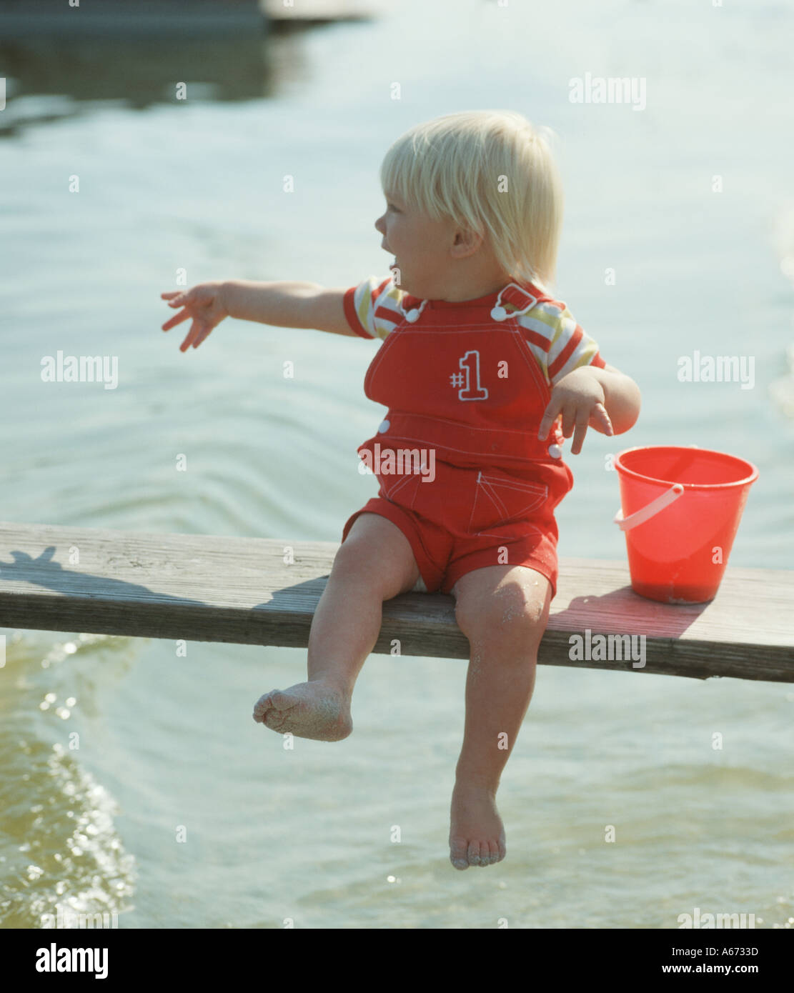 Small boy with toy pail on dock Stock Photo - Alamy