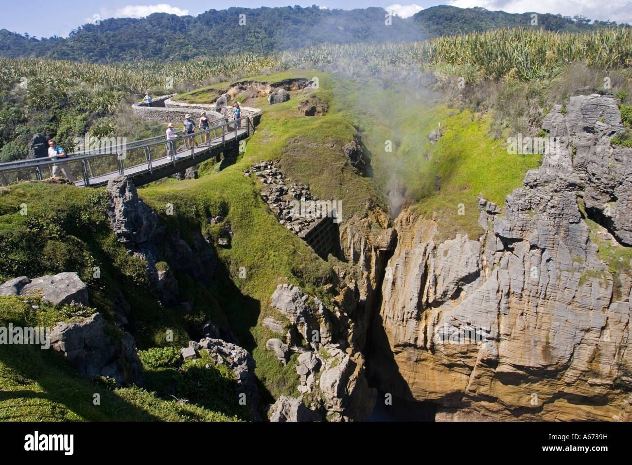 Visitors watching blowhole in limestone cliffs Pancake Rocks Punakaiki ...