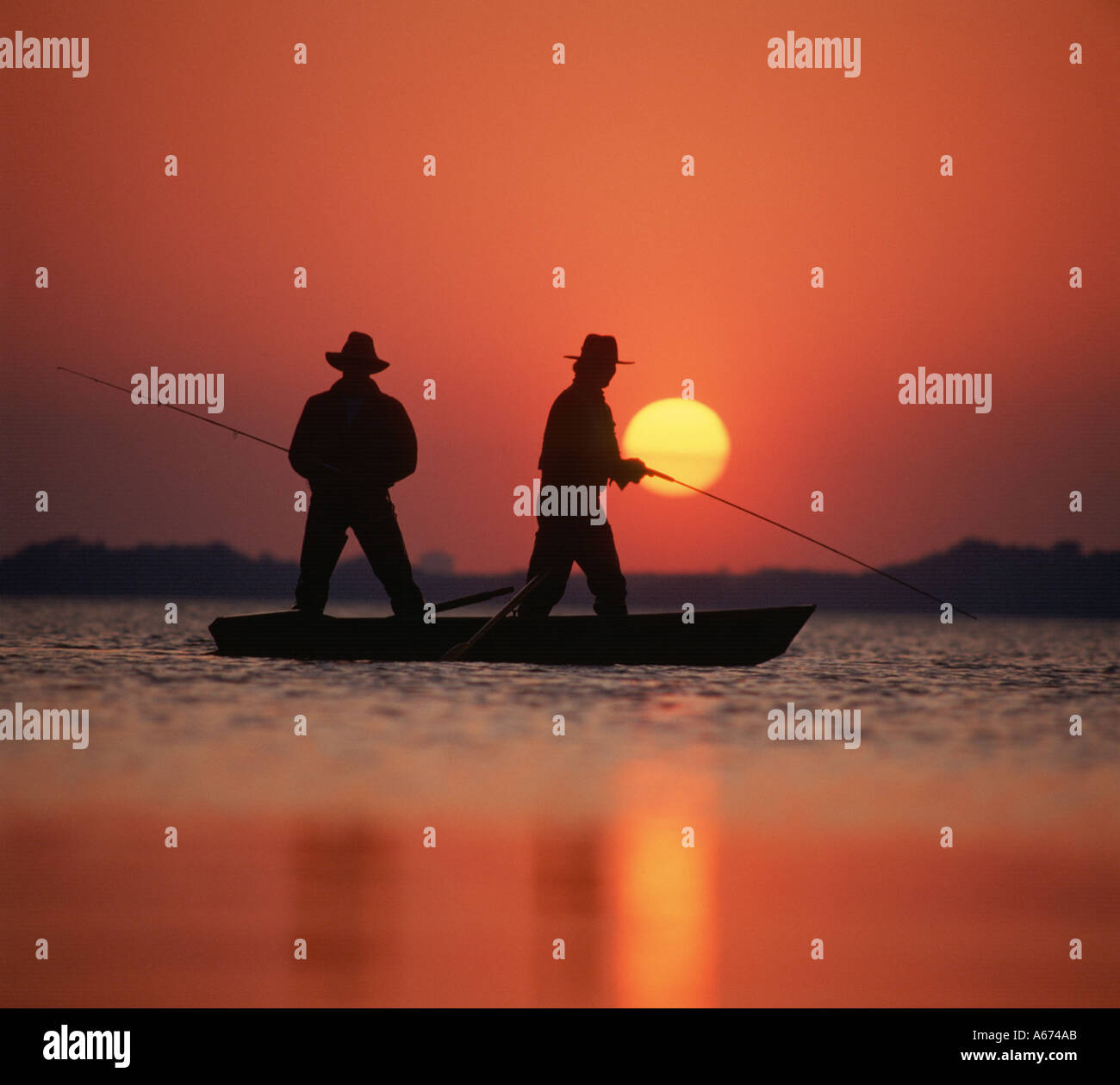 two men fishing at sunset in small boat Stock Photo - Alamy