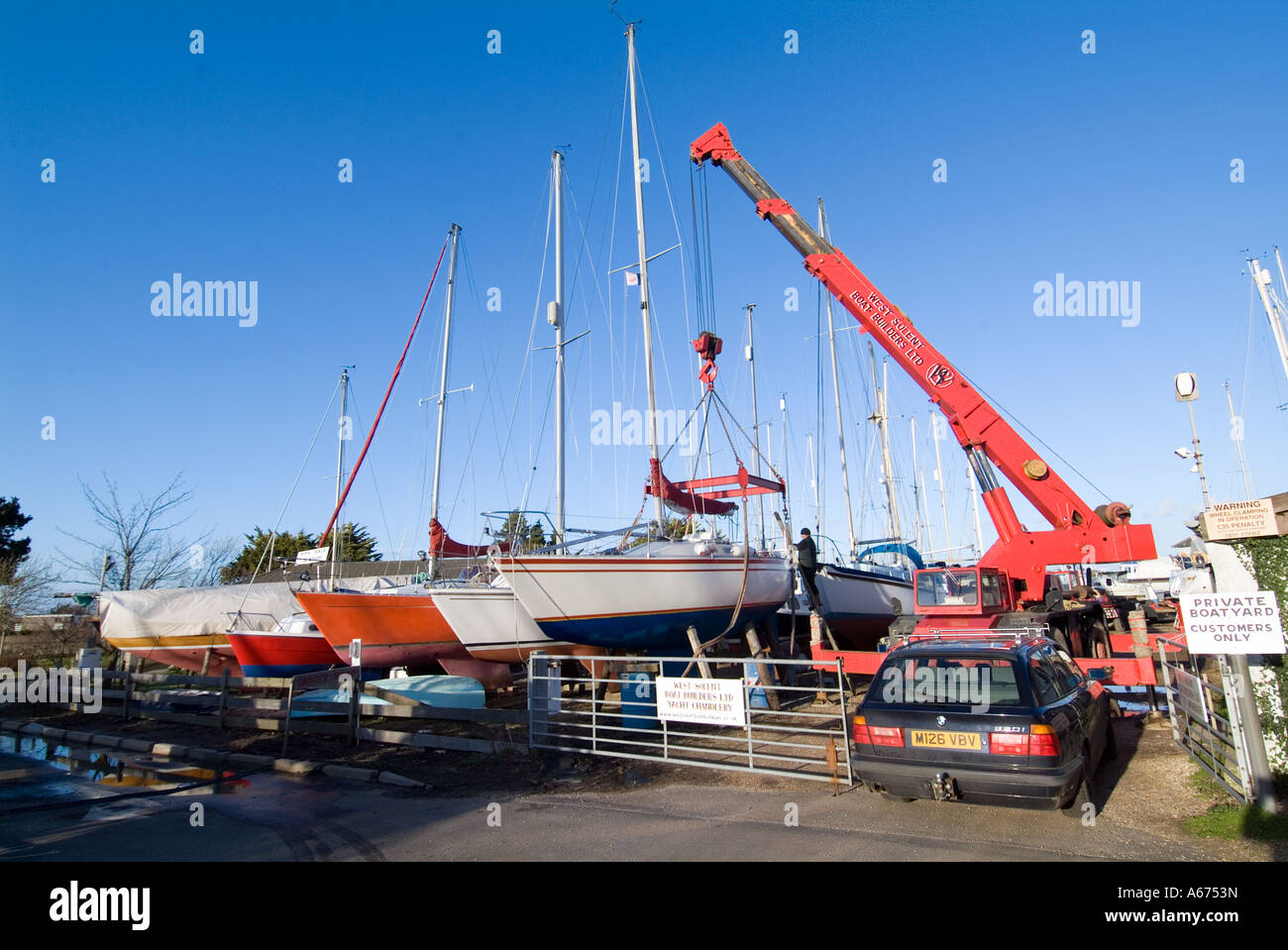 crane lifting a yacht out of the water and onto stilts in a marina ...