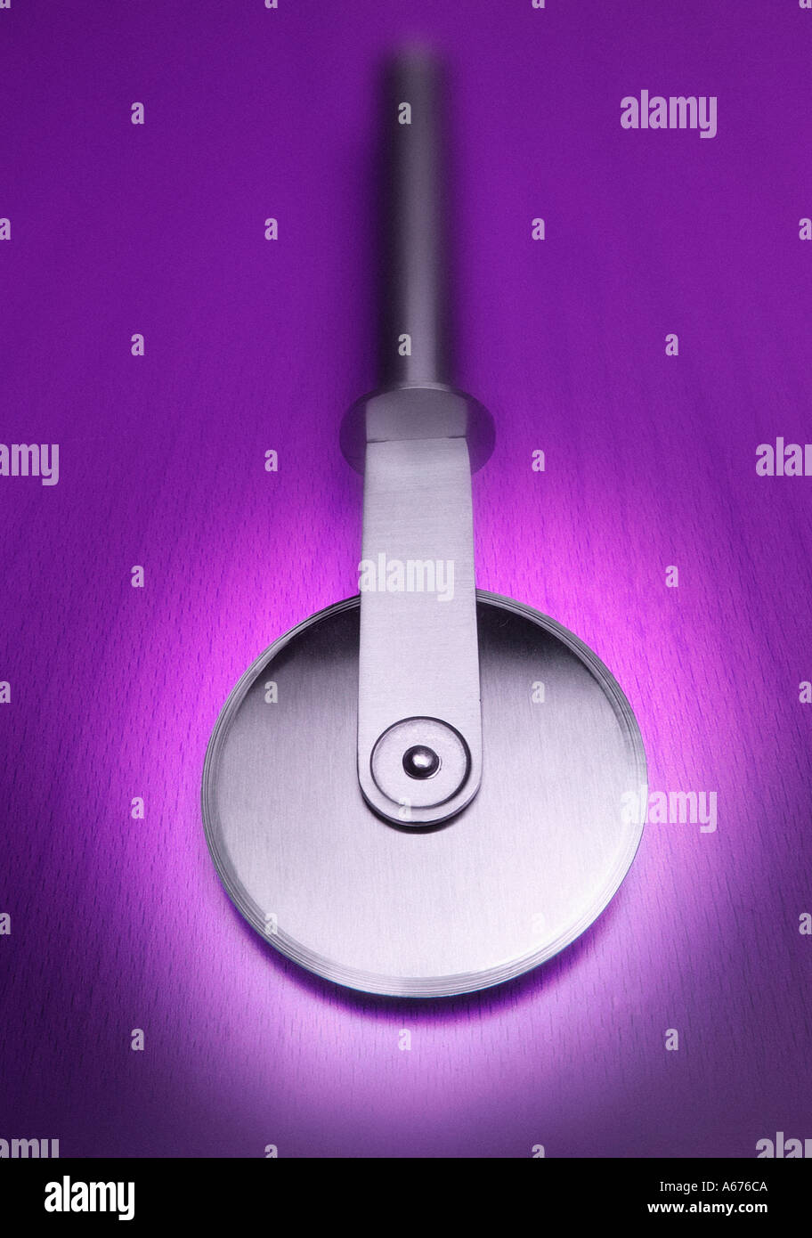 Stainless steel pizza cutter on purple background Stock Photo - Alamy