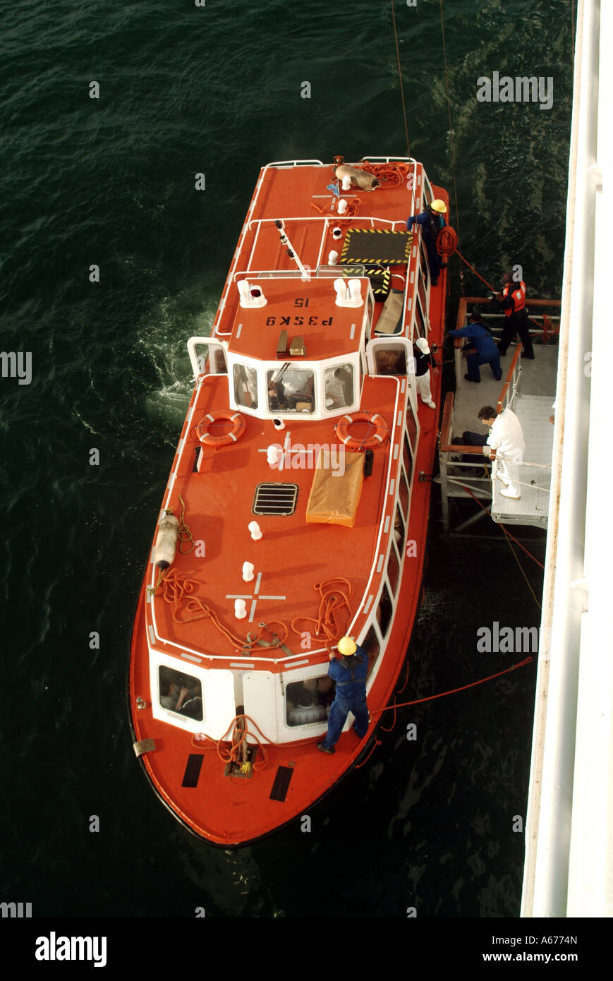 Aerial view crew bringing tender lifeboat alongside cruise ship liner ...