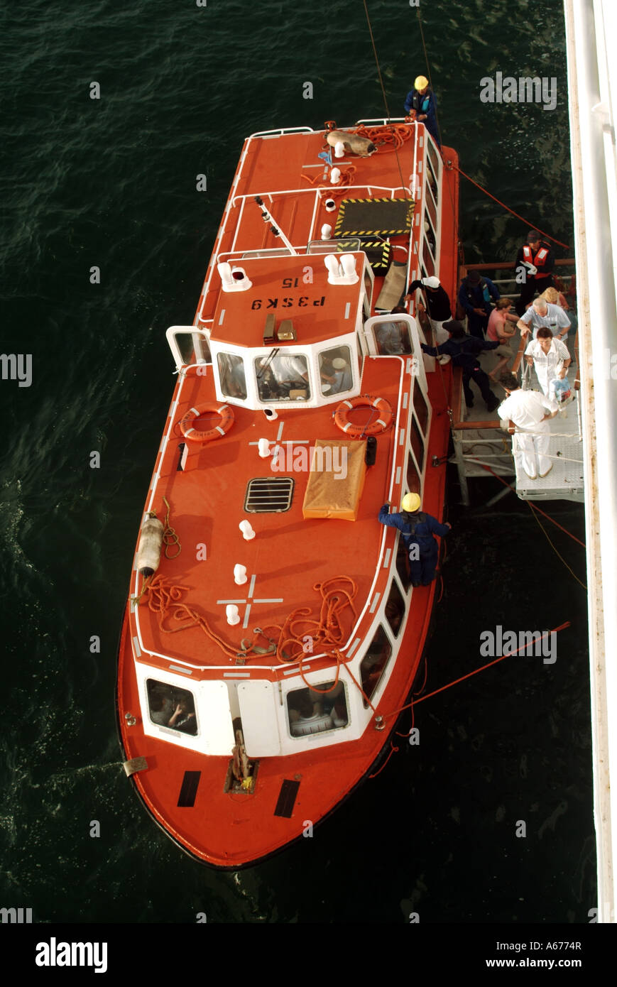Crew supervise unloading passengers off tender lifeboat onto cruise ...