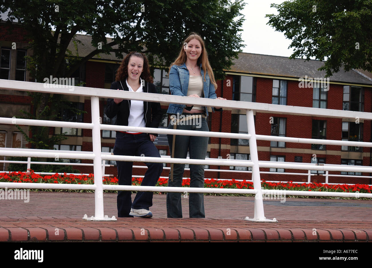 2 teenagers standing outside leaning against metal railings Stock Photo ...