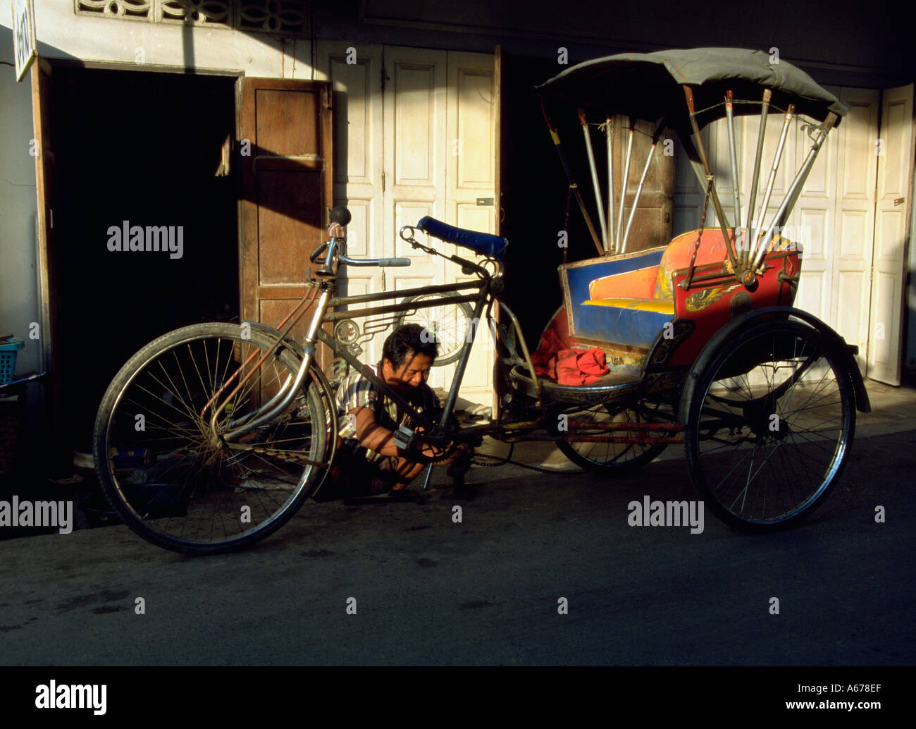 Cyclo driver fine tuning his tricycle Stock Photo - Alamy