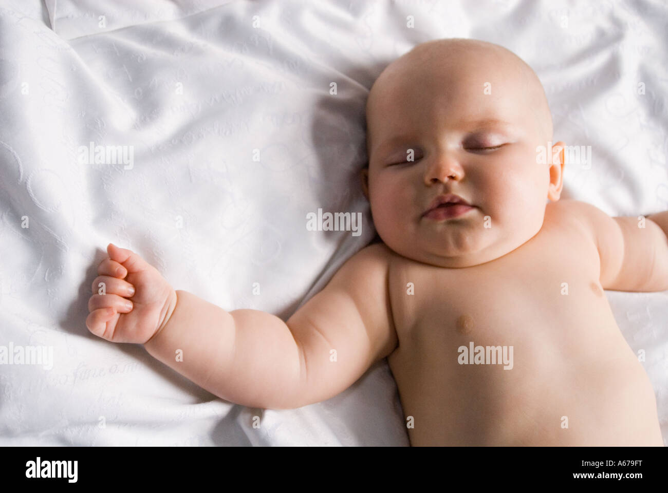 baby lying on its back asleep on a bed Stock Photo - Alamy