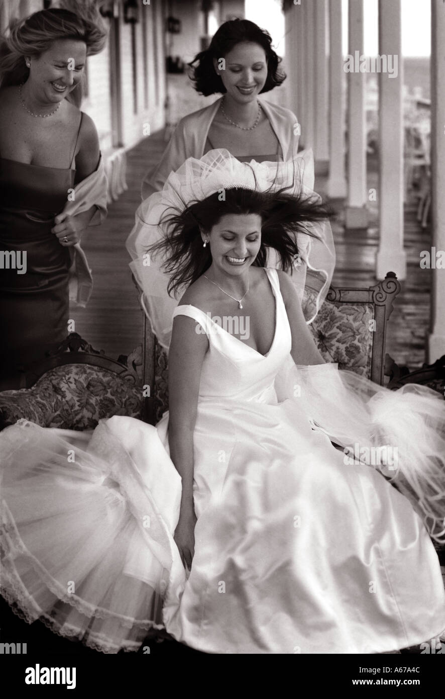 Bride holding down gown as wind blows with bridesmaids standing by ...