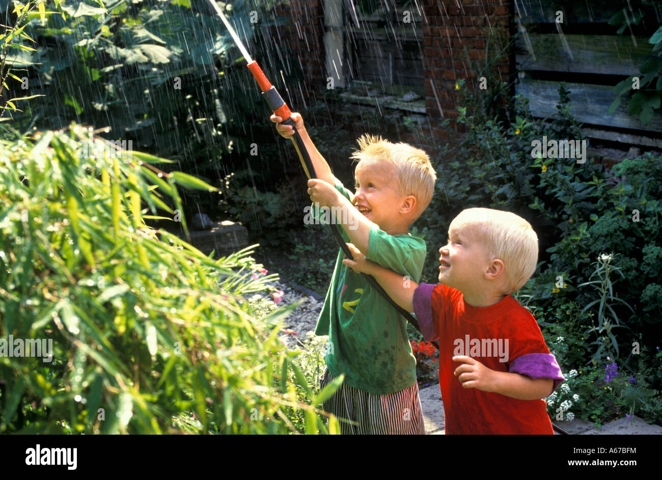 Two children watering the garden Stock Photo - Alamy