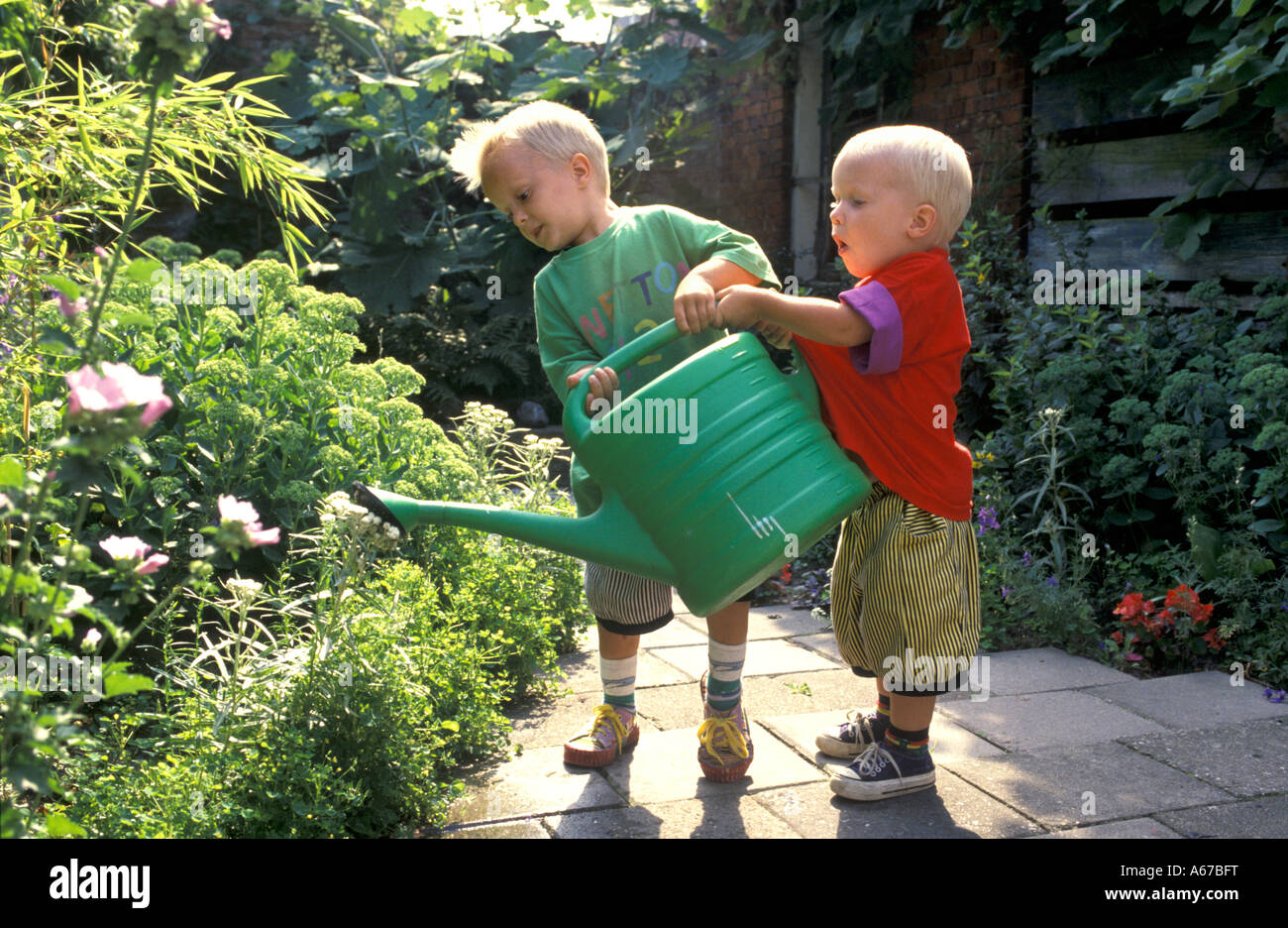 Two children watering the garden Stock Photo - Alamy